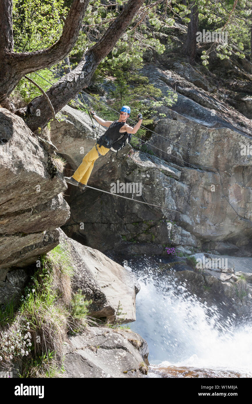 Man flexing muscles while climbing rock via ferrata towards Stuibenfall ...