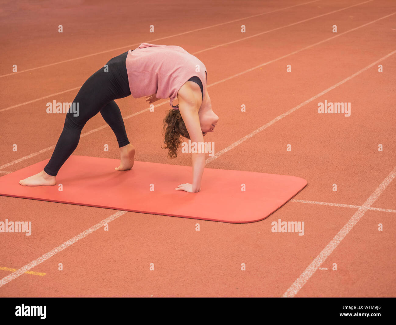 Woman bending over backwards in yoga position at athletics hall on ...