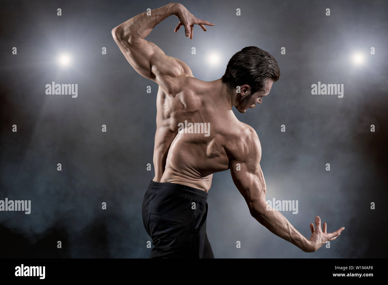 Muscular man flexing muscles while posing on stage Stock Photo - Alamy