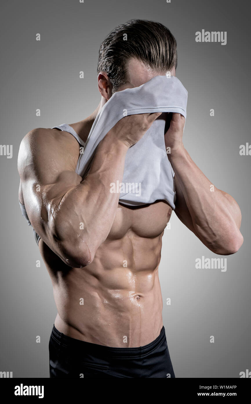 Muscular young man wiping off sweat after exercising in gym Stock Photo ...