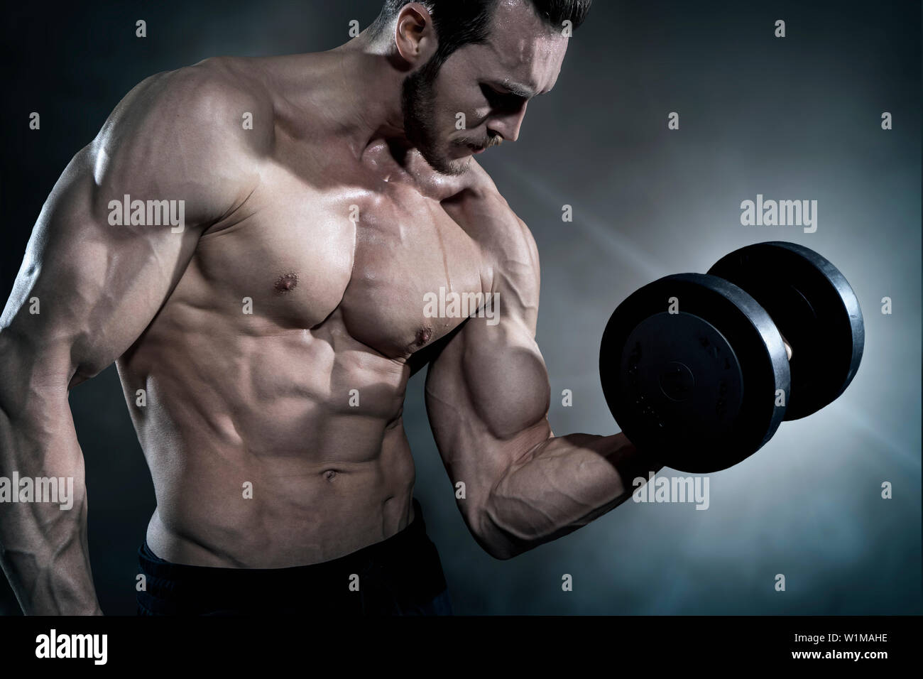 Muscular man doing exercise with dumbbells Stock Photo - Alamy