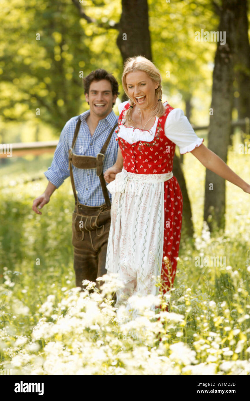 Couple running hand in hand over a meadow Stock Photo - Alamy