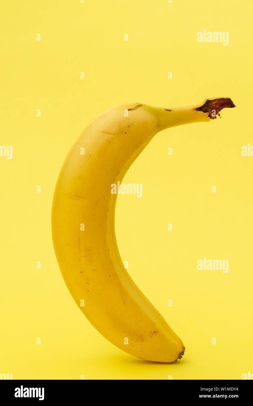 One banana standing on yellow background Stock Photo - Alamy