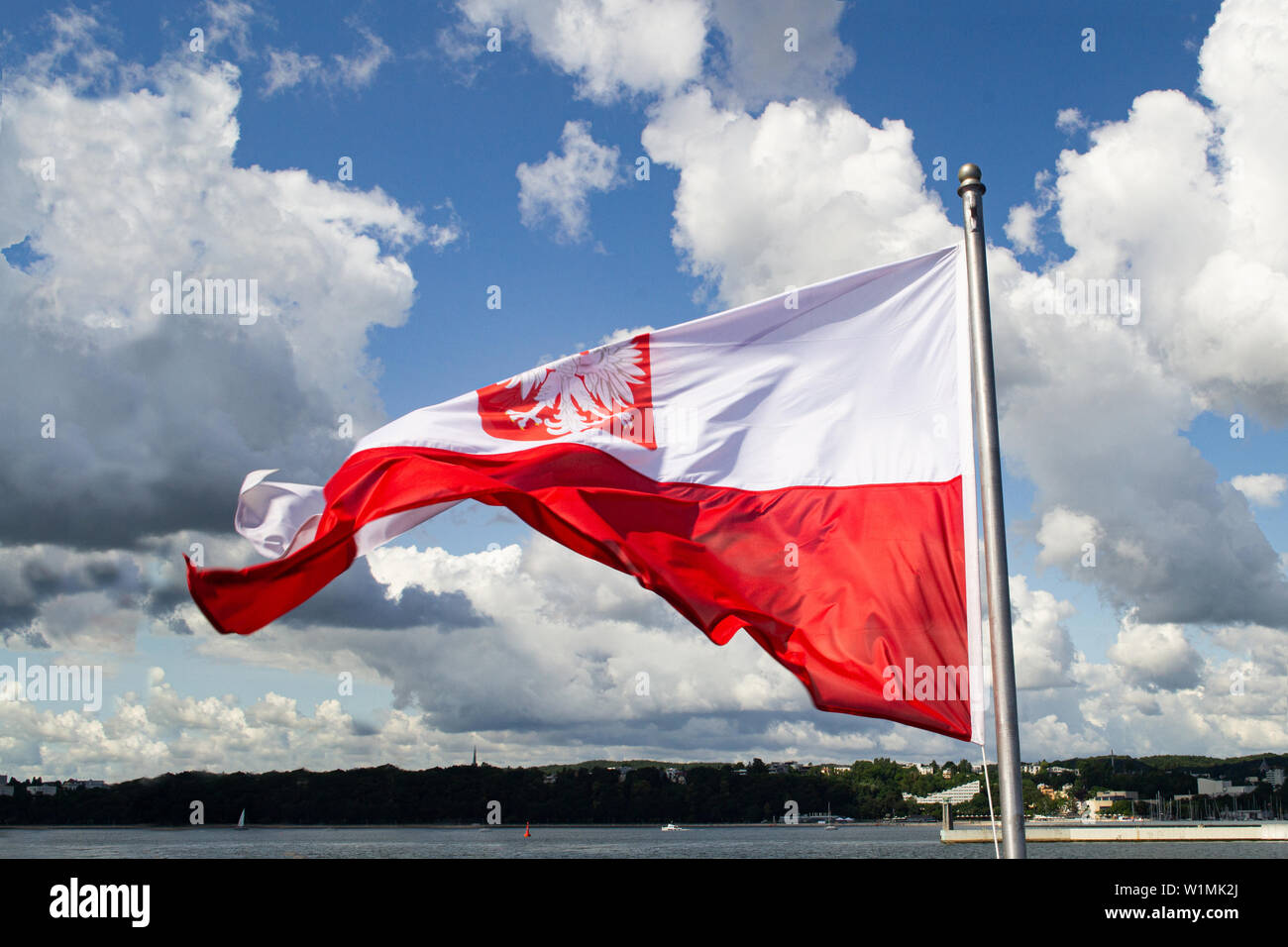 Flag of Poland. Poland national flag with emblem on cloudy blue sky ...
