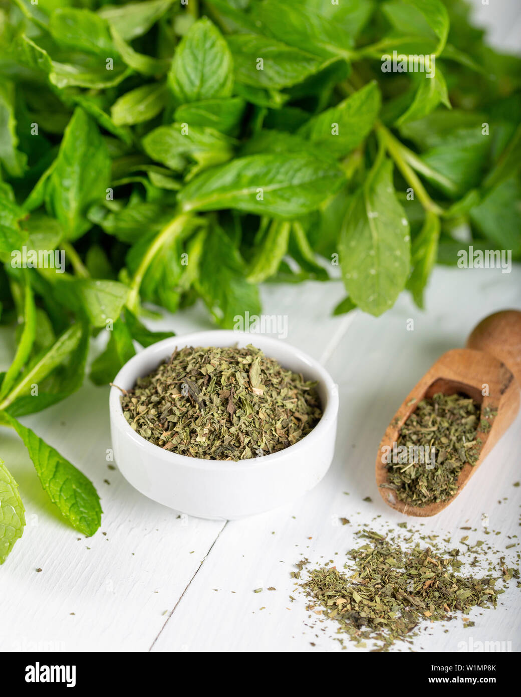 Dried peppermint in a white bowl and a bunch of fresh mint, on wooden ...