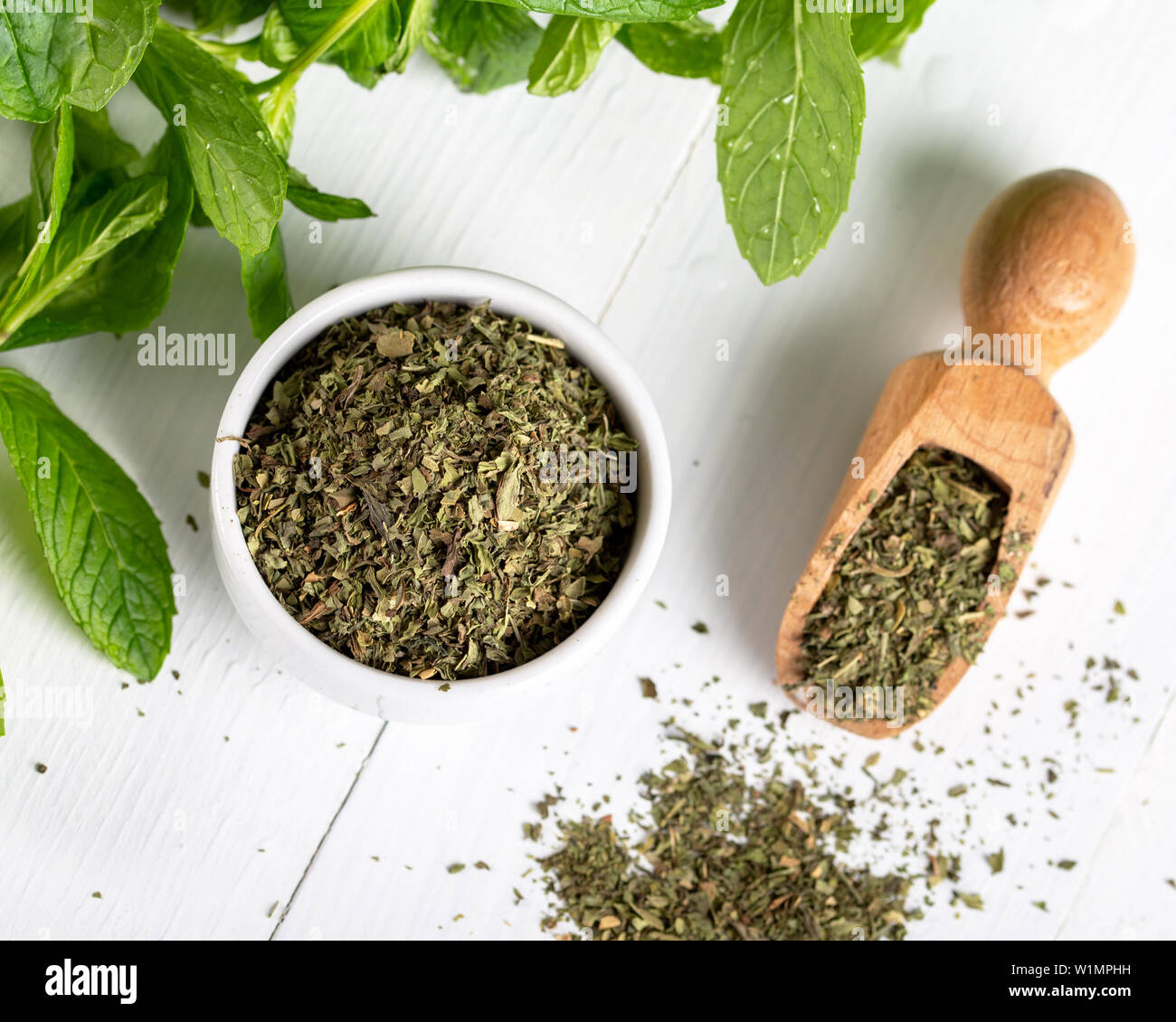 Dried peppermint in a white bowl and a bunch of fresh mint, on wooden ...