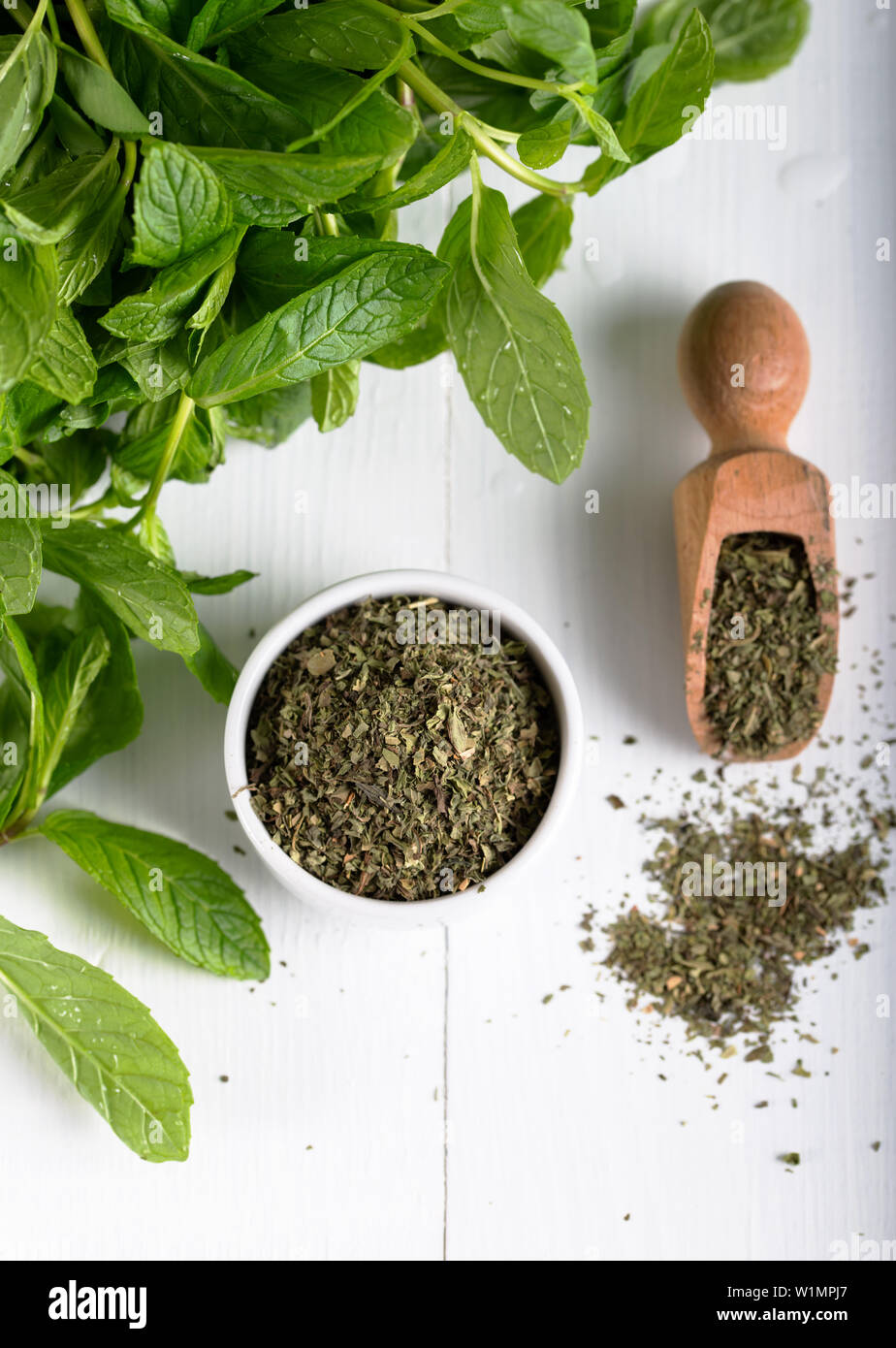 Dried peppermint in a white bowl and a bunch of fresh mint, on wooden ...
