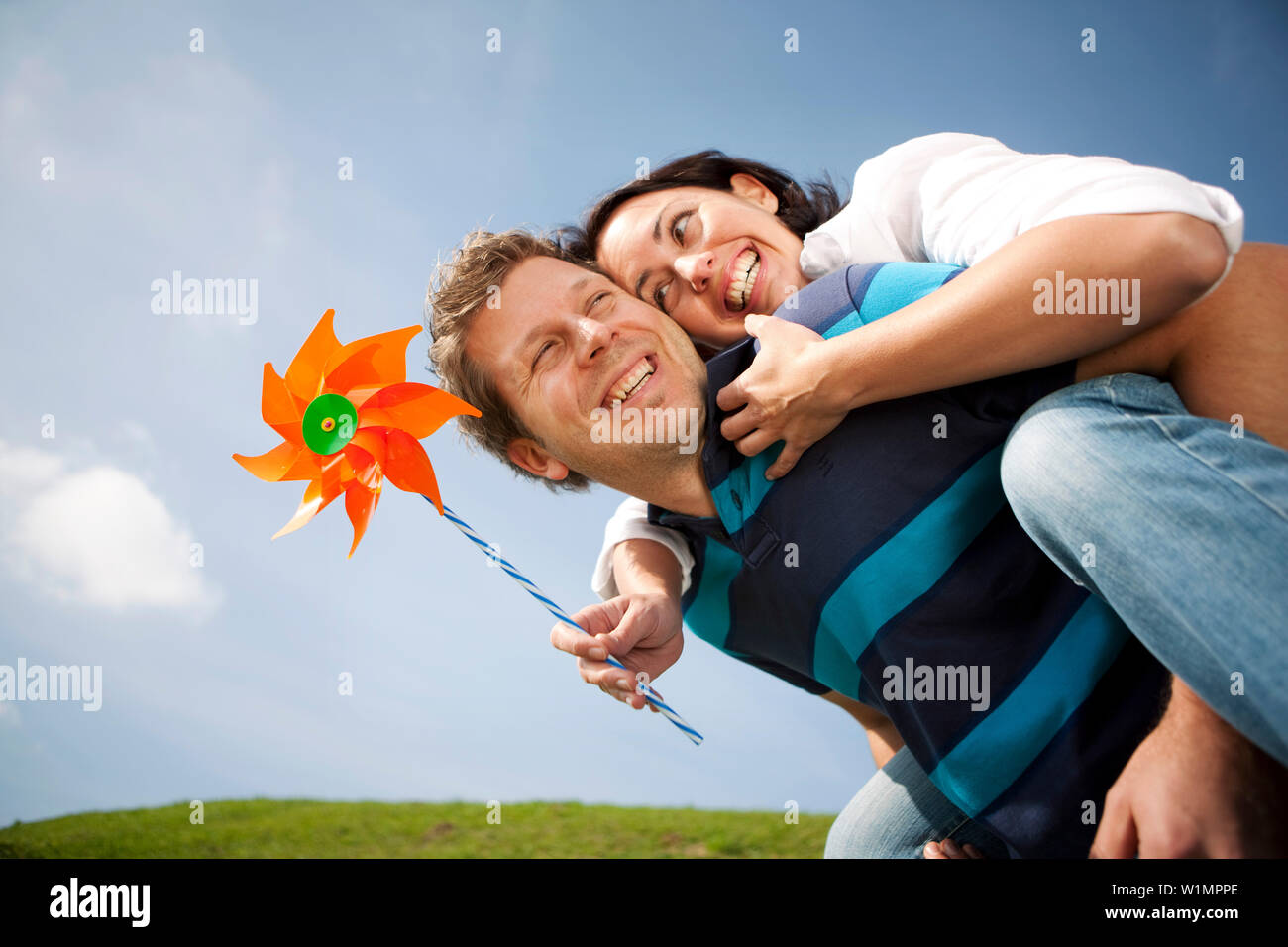 Mid adult man giving woman with pinwheel a piggyback ride Stock Photo ...