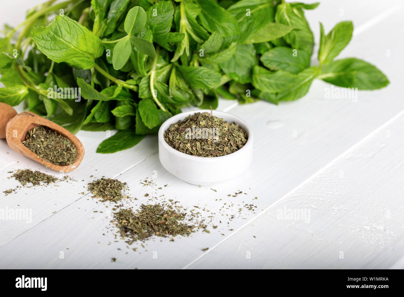 Dried peppermint in a white bowl and a bunch of fresh mint, on wooden ...