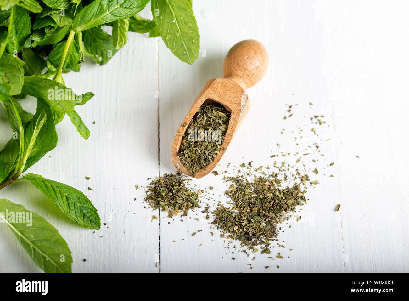 Dried peppermint in a white bowl and a bunch of fresh mint, on wooden ...