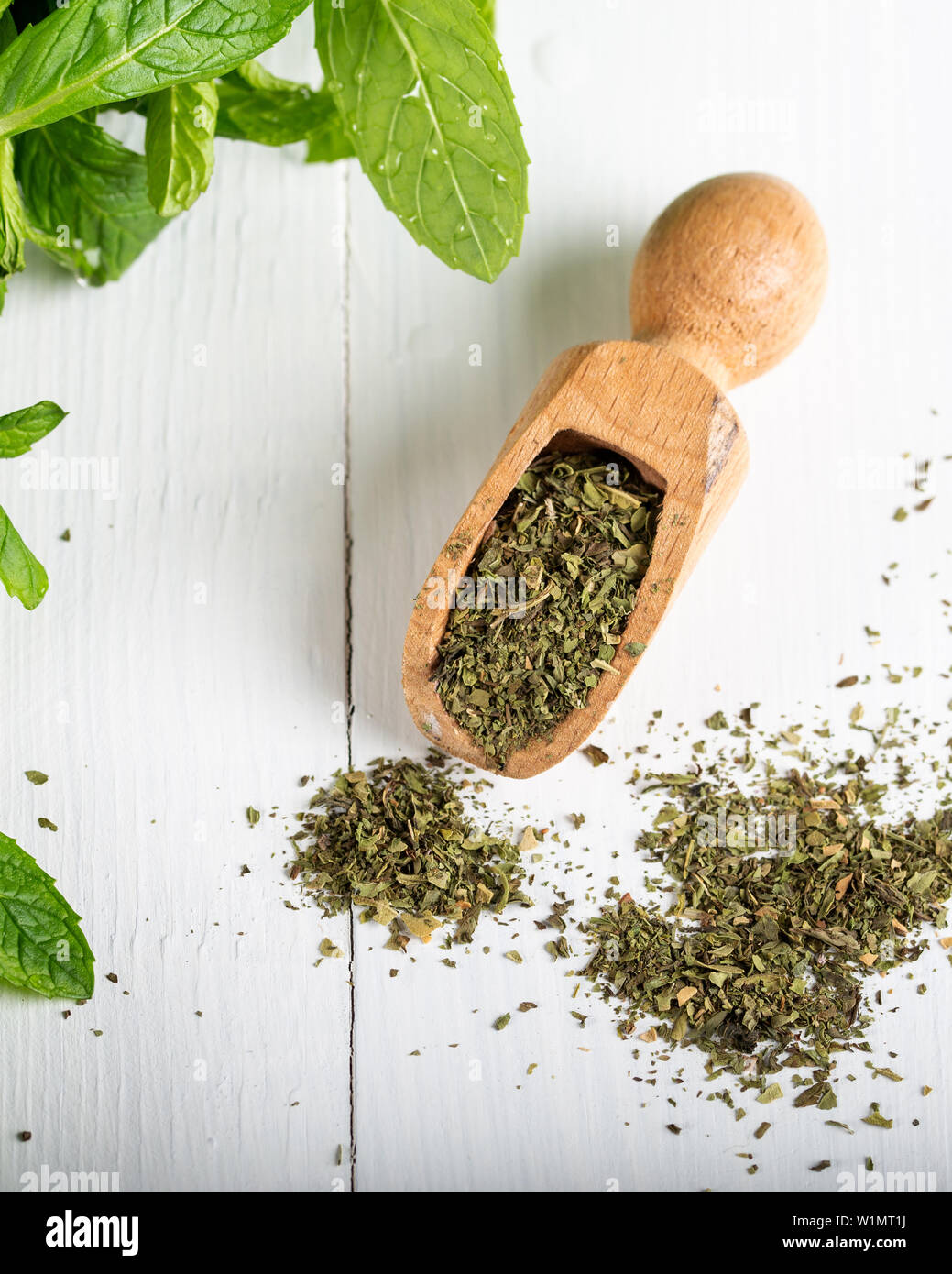 Dried peppermint in a white bowl and a bunch of fresh mint, on wooden ...