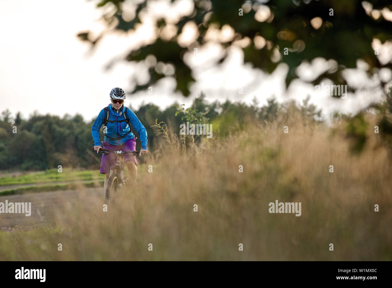 Woman riding bike through field hi-res stock photography and images - Alamy