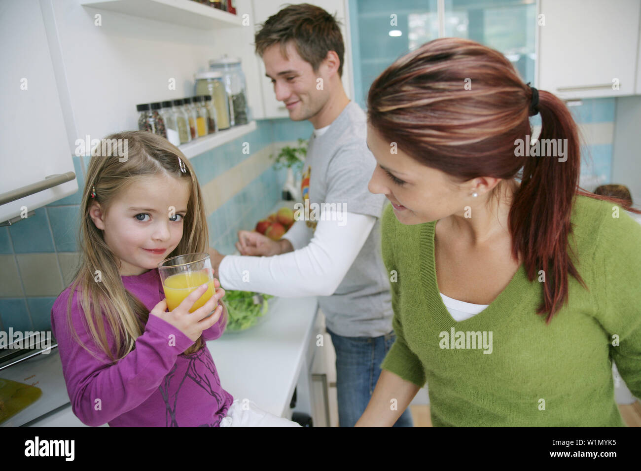 Family in kitchen, daughter drinking a glass of juice, Munich, Germany ...