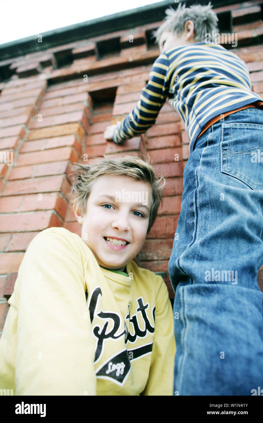 Boy giving friend a bunk-up over a wall Stock Photo - Alamy
