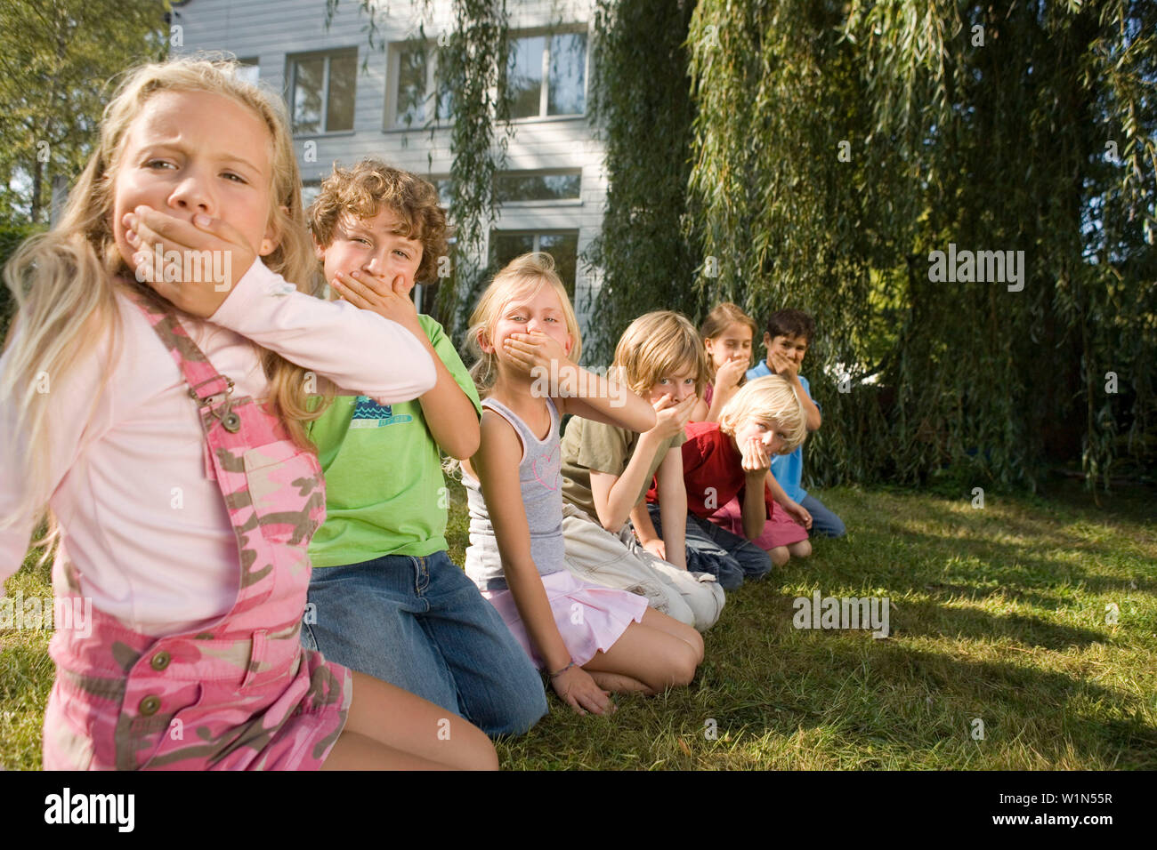 Children crouching on grass and making grimaces, children's birthday ...