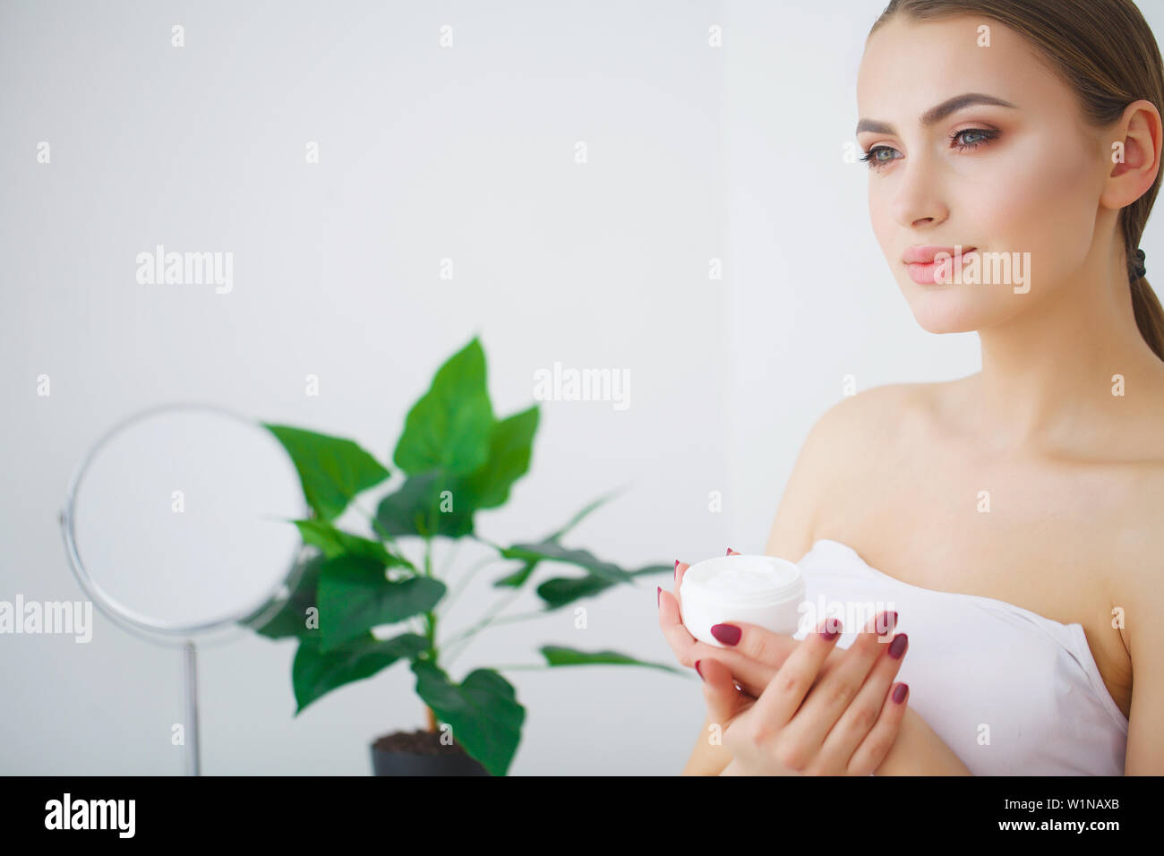 Spa. Beautiful model applying cosmetic cream treatmen on her face Stock ...