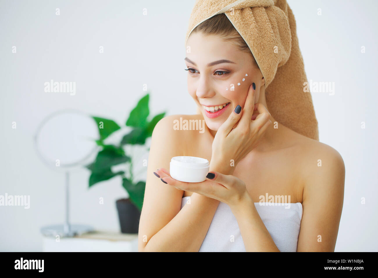 Spa. Beautiful model applying cosmetic cream treatmen on her face Stock ...