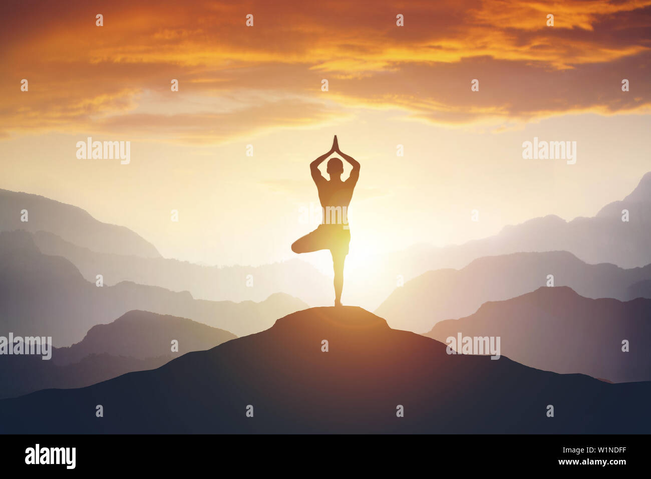 Man meditating on high mountain in sunset background Stock Photo - Alamy