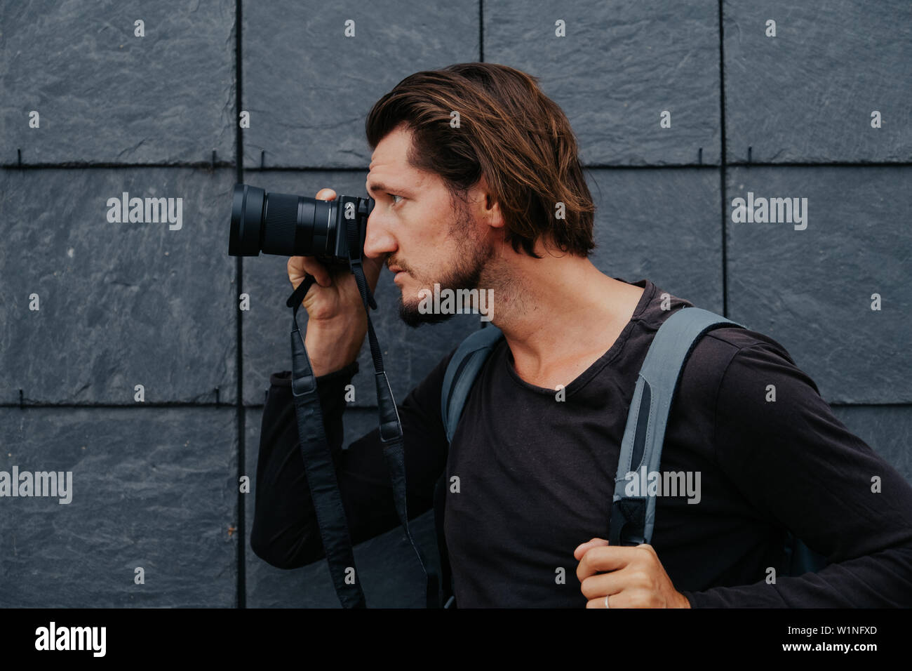 Stylish hipster photographer in a big city with a camera and a backpack ...