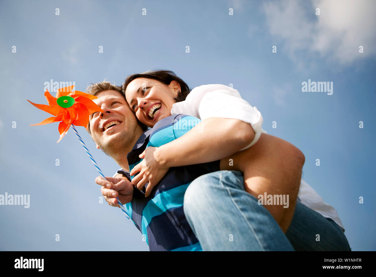 Mid adult man giving woman with pinwheel a piggyback ride Stock Photo ...