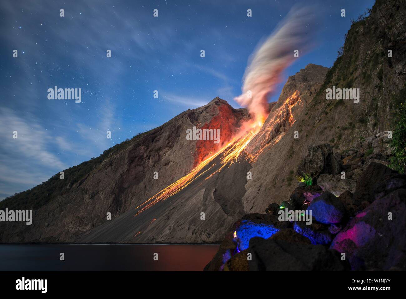 Eruption of Batu Tara volcano at full moon with the Milky Way. Ash ...