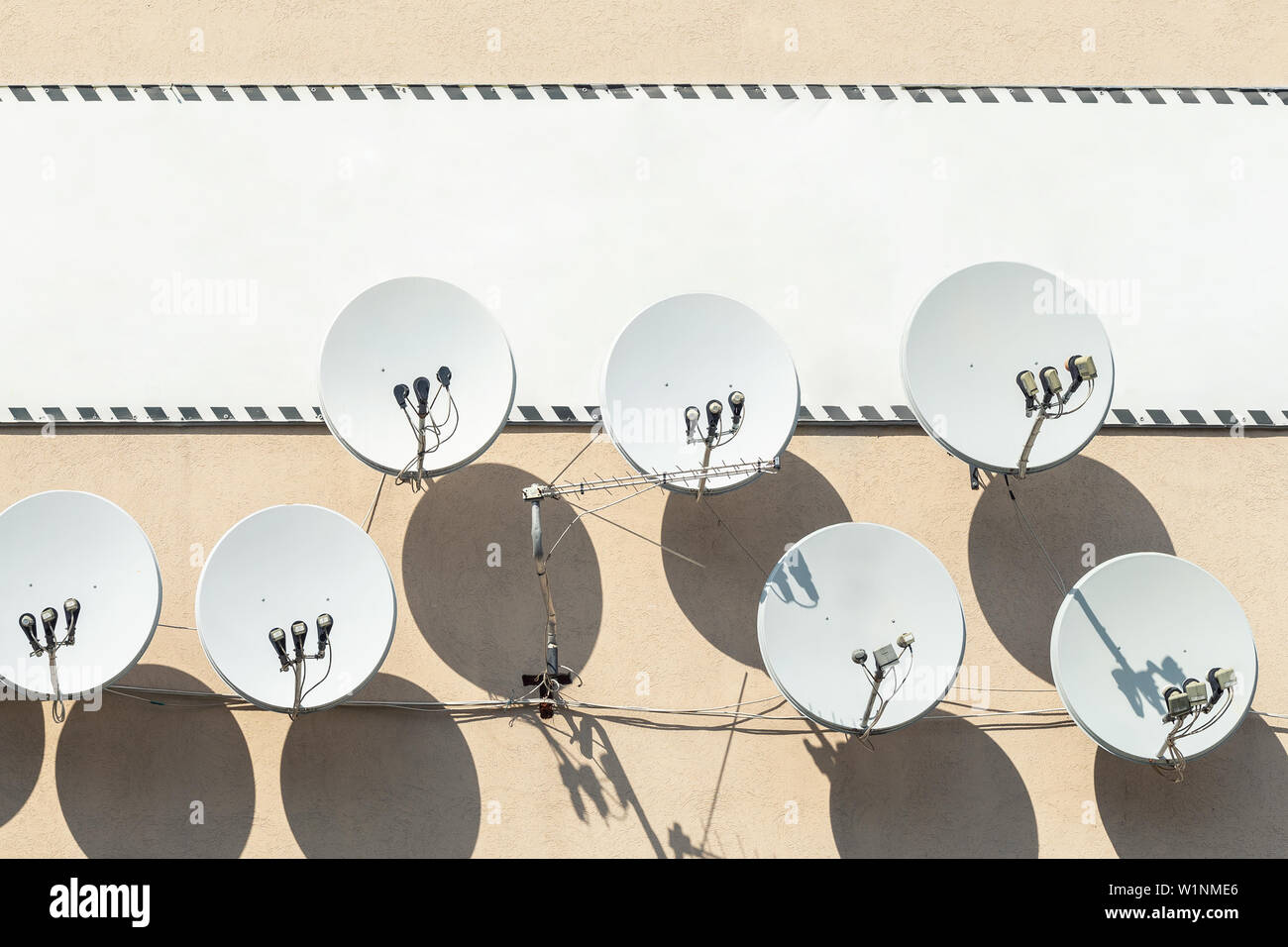 Many satellite dish antenna hanged on building wall with big white ...