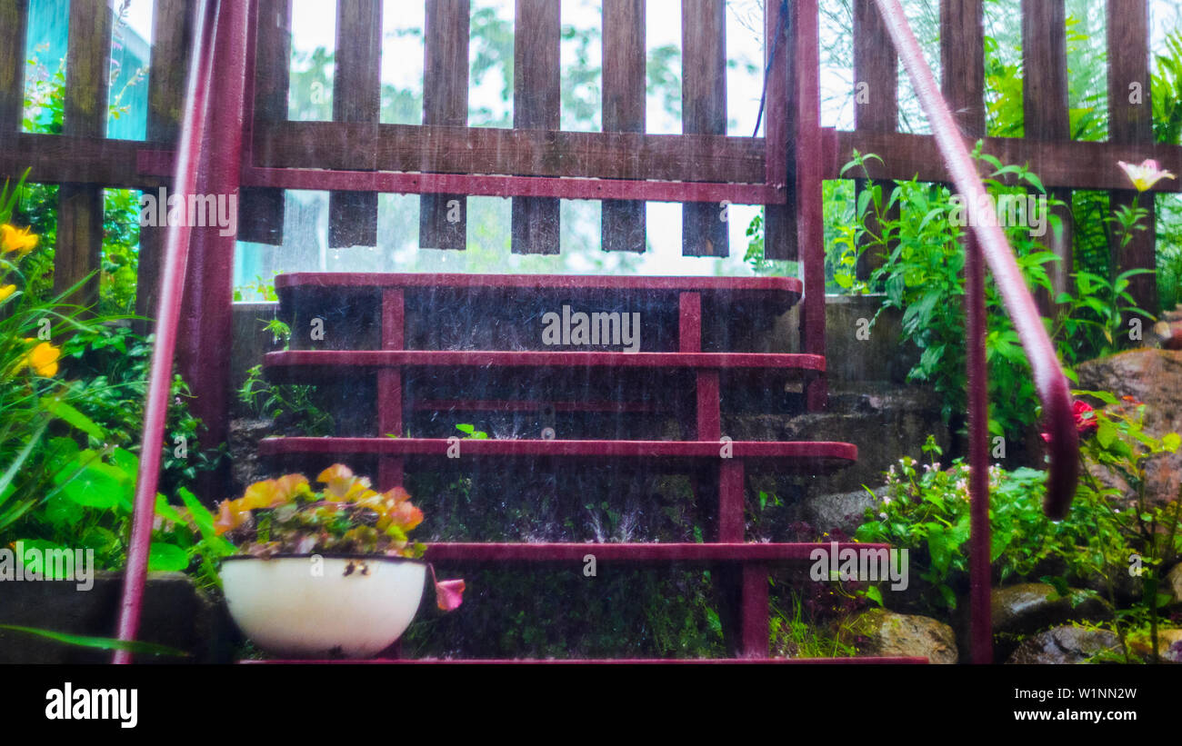 Heavy summer rain in the yard of a private house. Wooden staircase in ...