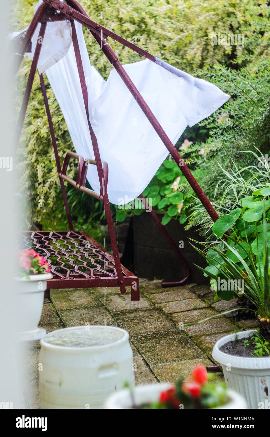 Metal swing in the yard after a rainstorm. Rainwater filled the white ...