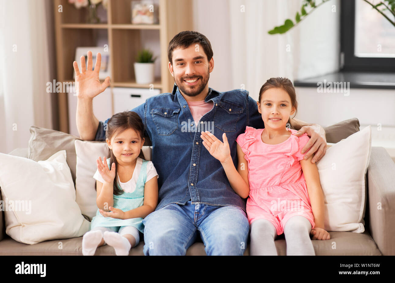 happy father with daughters waving hands at home Stock Photo - Alamy