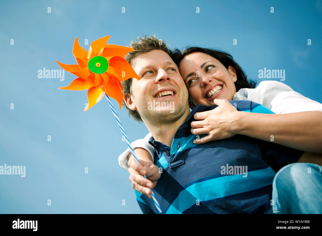 Mid adult man giving woman with pinwheel a piggyback ride Stock Photo ...