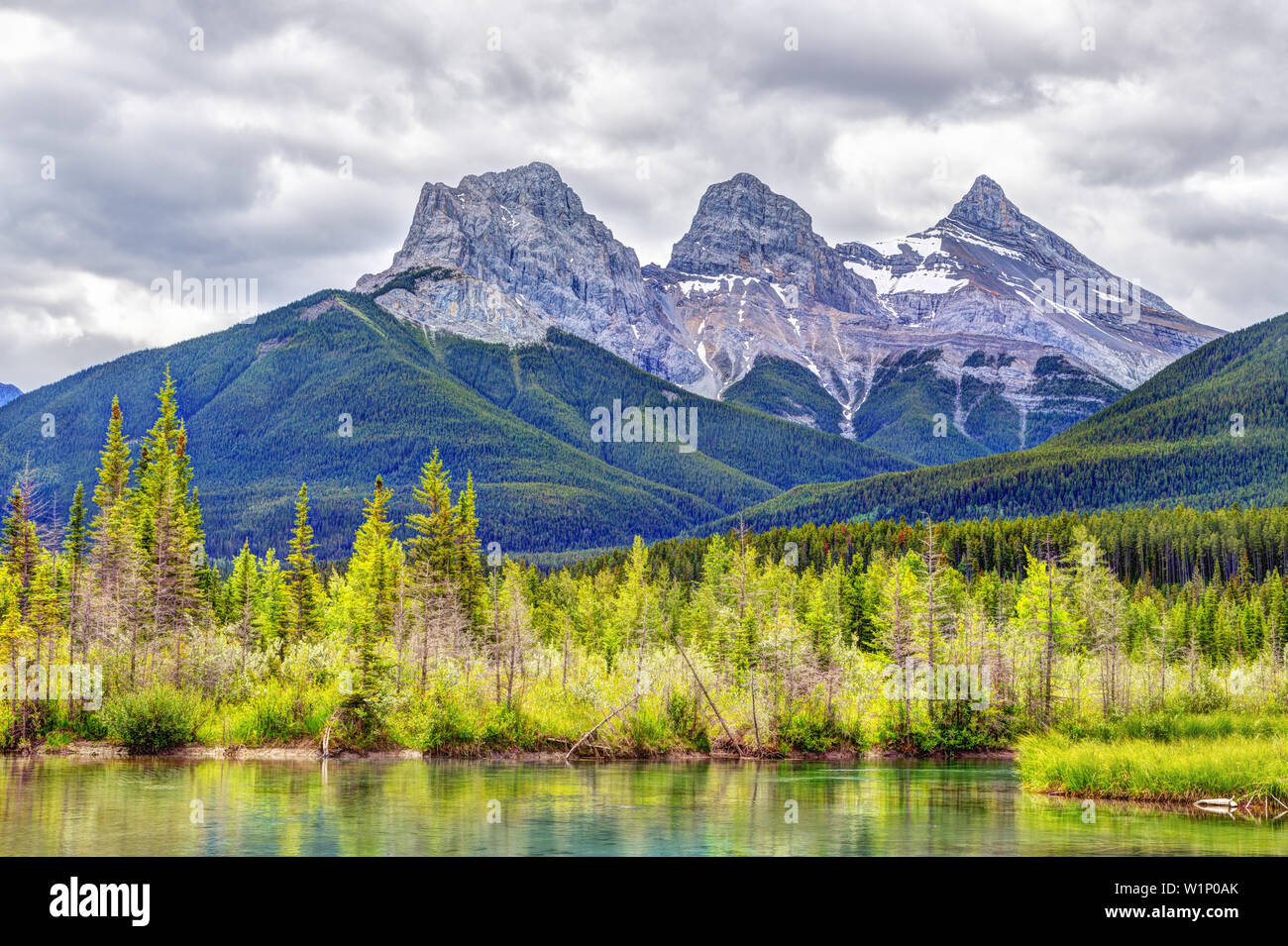 Canmore's famous Three Sisters mountain peaks beside the Bow River in the southern Banff range ...
