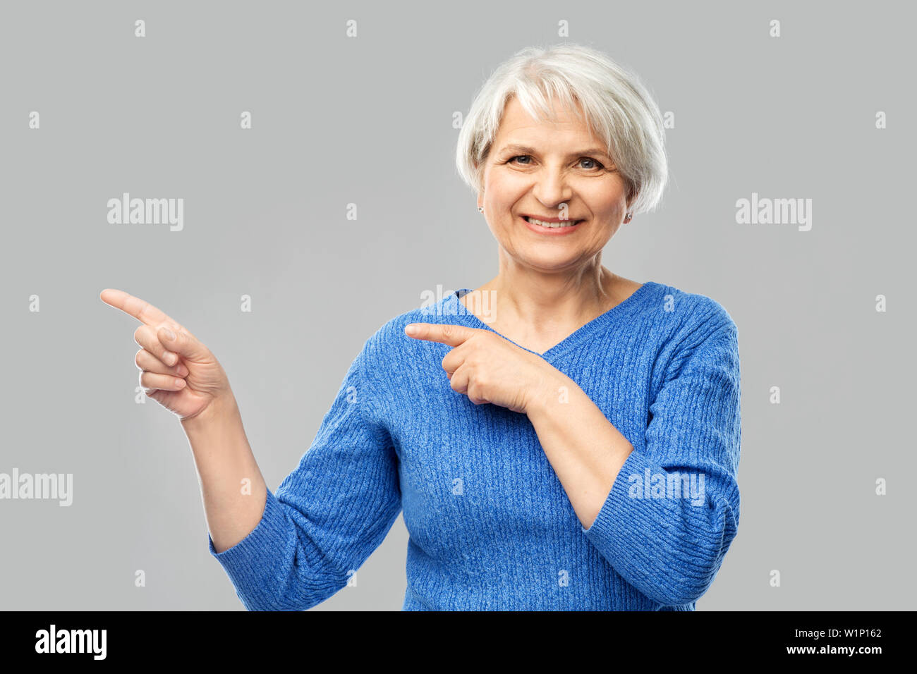 smiling senior woman pointing fingers to something Stock Photo - Alamy