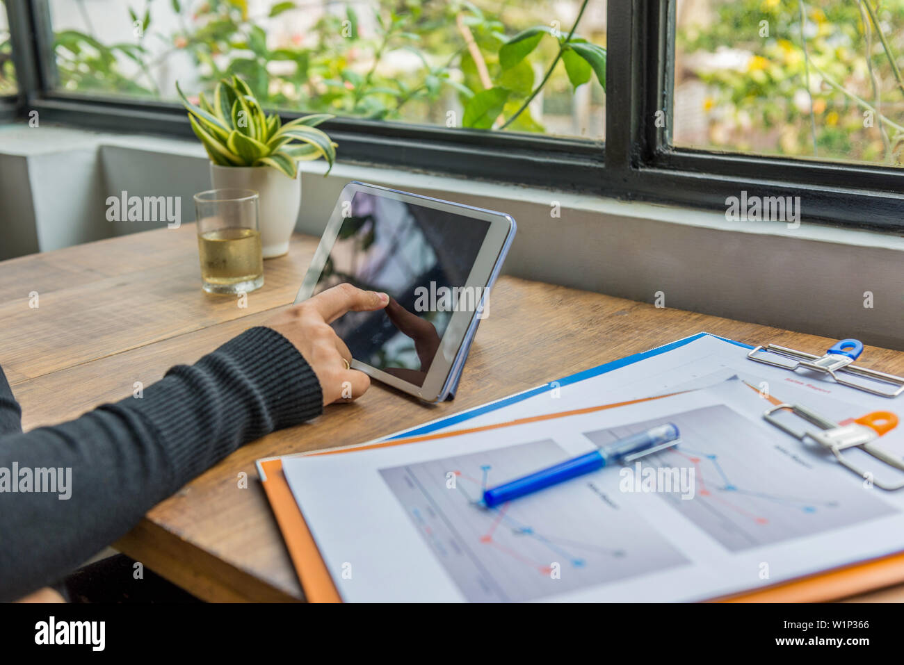 Female hand tapping tablet screen at workplace next to window Stock ...