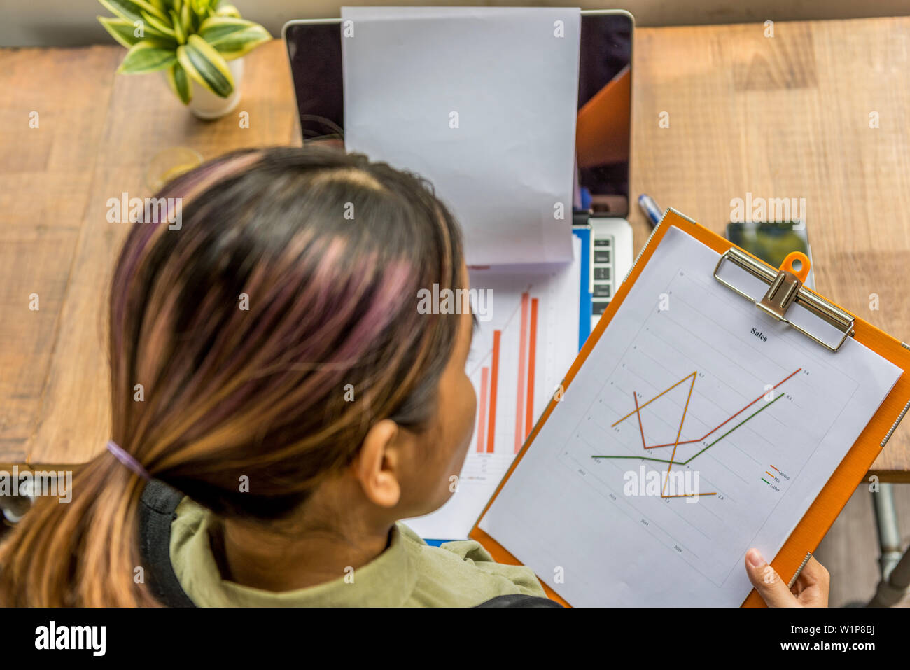 Asian freelancer working on sales diagram documents on rustic table ...