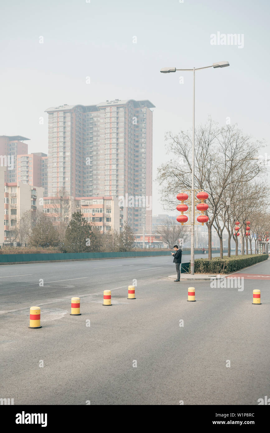 chinese man standing at uncrowded street looking at mobile phone, China ...