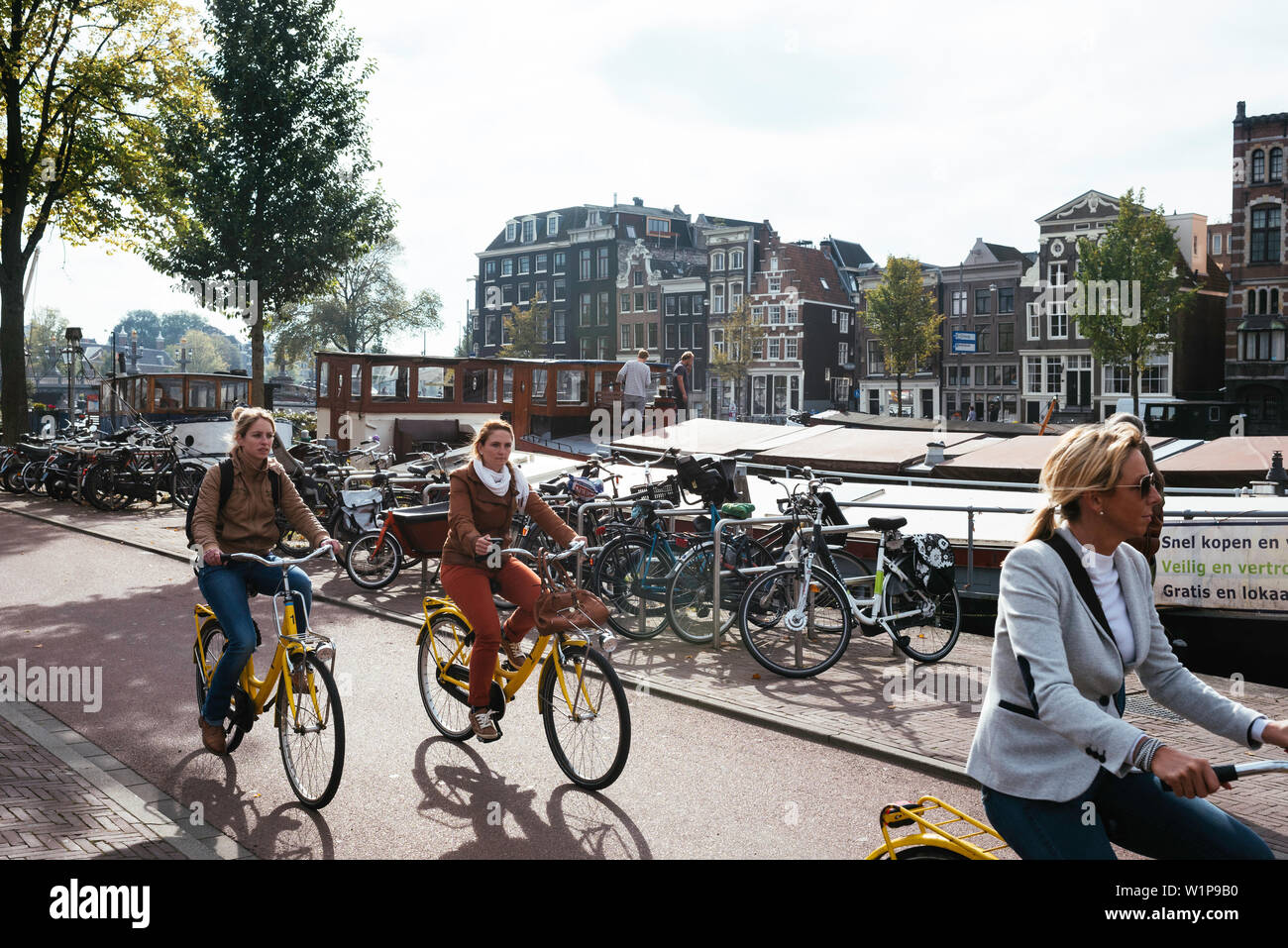 Young women riding bicycle in the Center along the Canal, Amsterdam ...