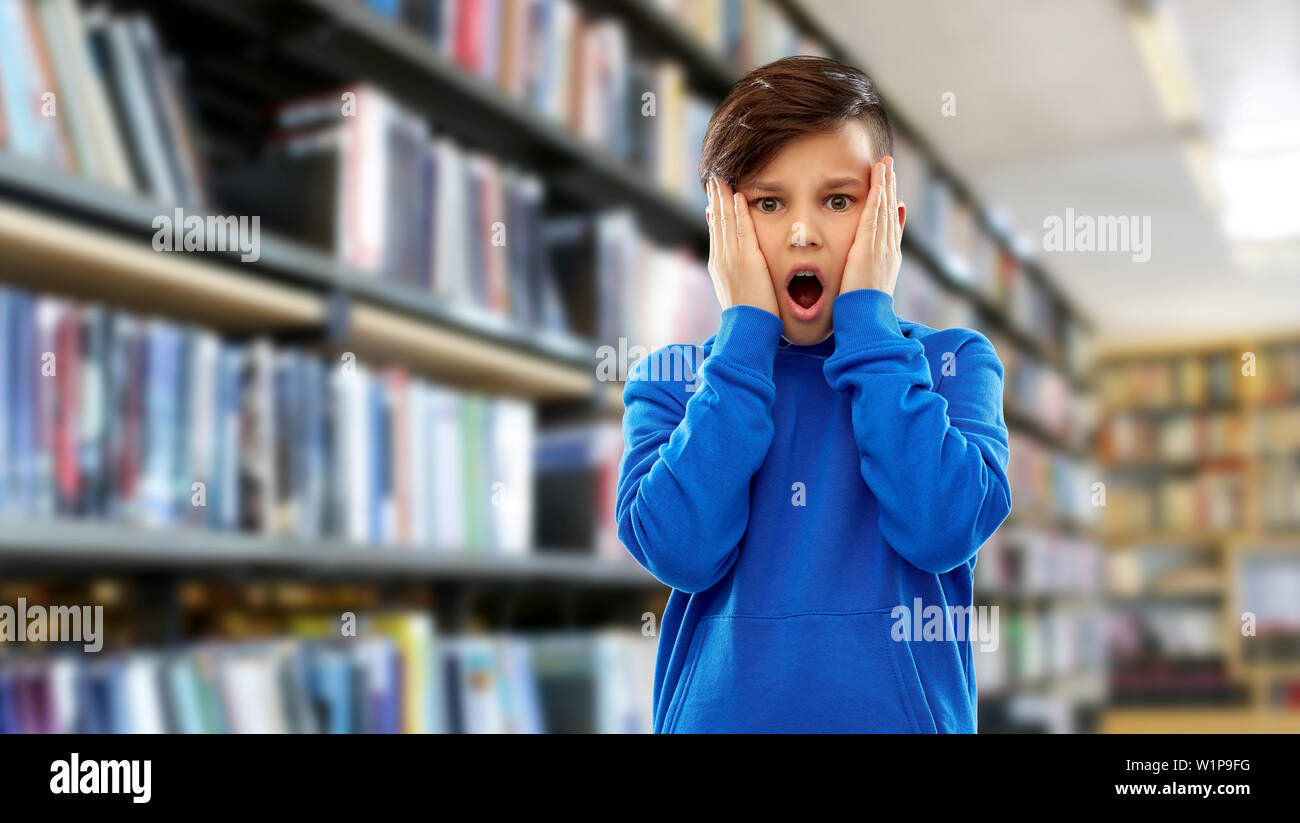 terrified boy over book shelves at library Stock Photo - Alamy