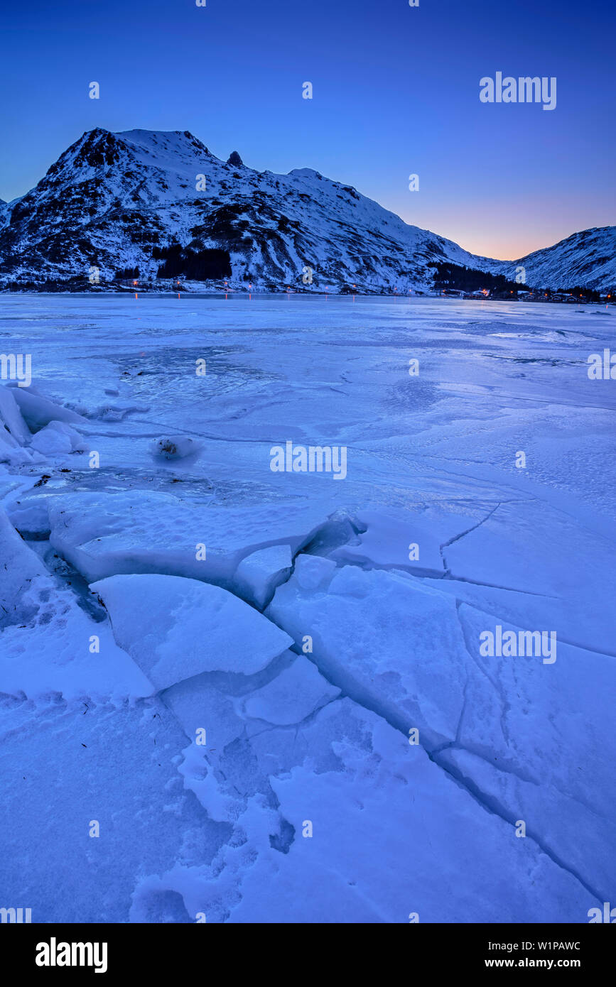 Icy coast with snow-covered mountains in background, Lofoten, Nordland ...