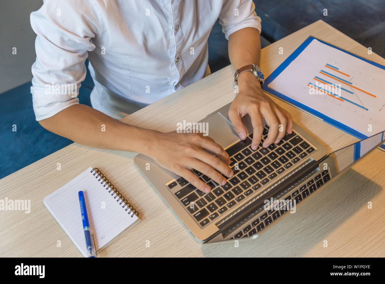 Human hands typing laptop keyboard next to graph document Stock Photo ...
