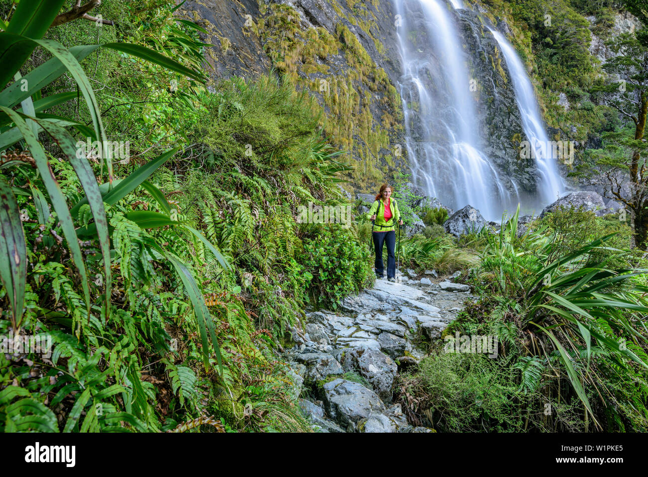 Woman hiking beneath waterfall, Earland Falls, Routeburn Track, Great ...