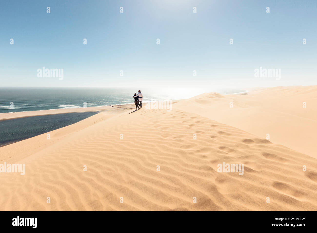 A couple in the dunes high above the lagoons of Sandwich Harbour ...