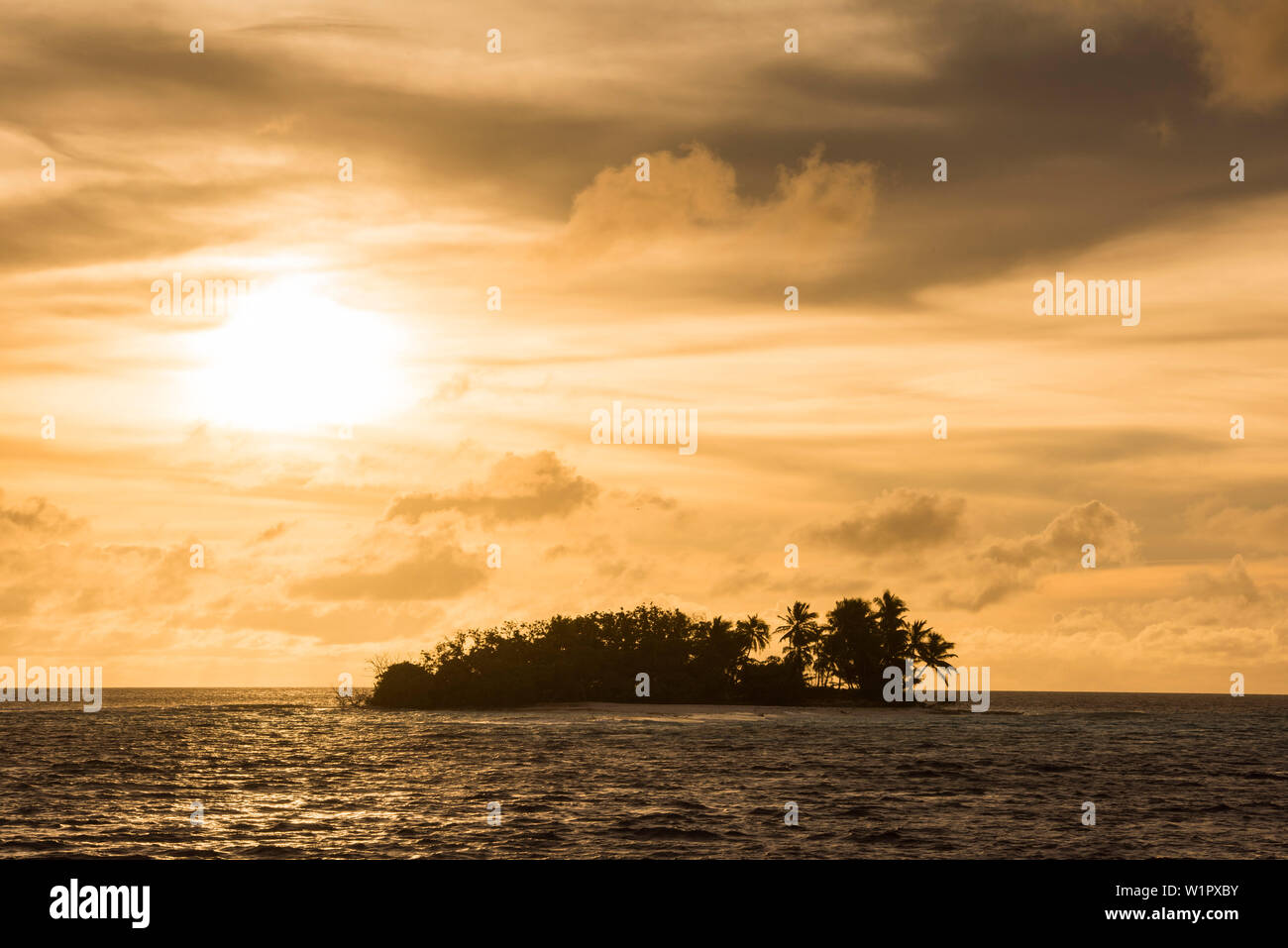 Late afternoon sun and wispy clouds paint the sky orange-yellow behind ...