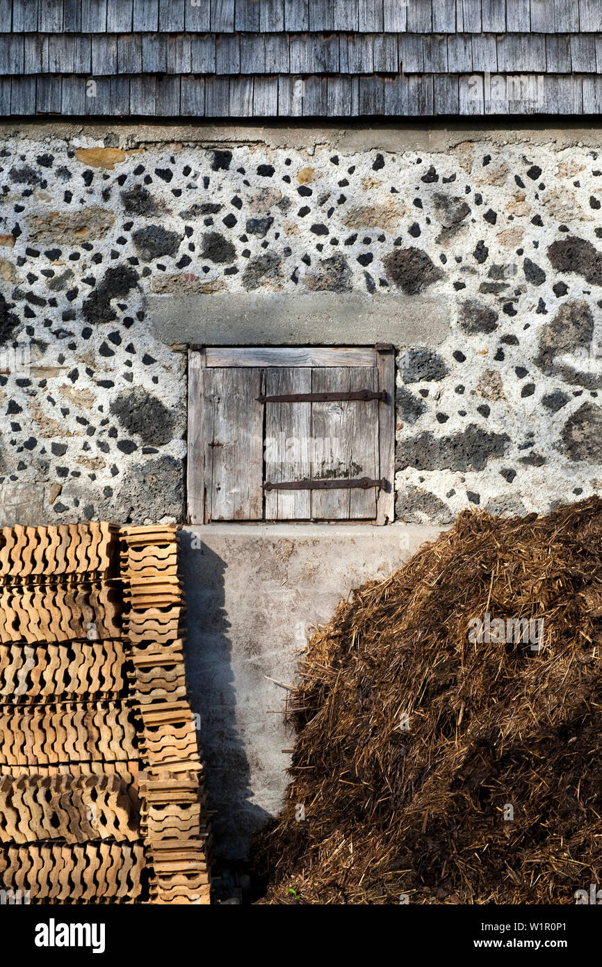 Stacked roof tiles and dung heap under a small wooden door; slag stone ...