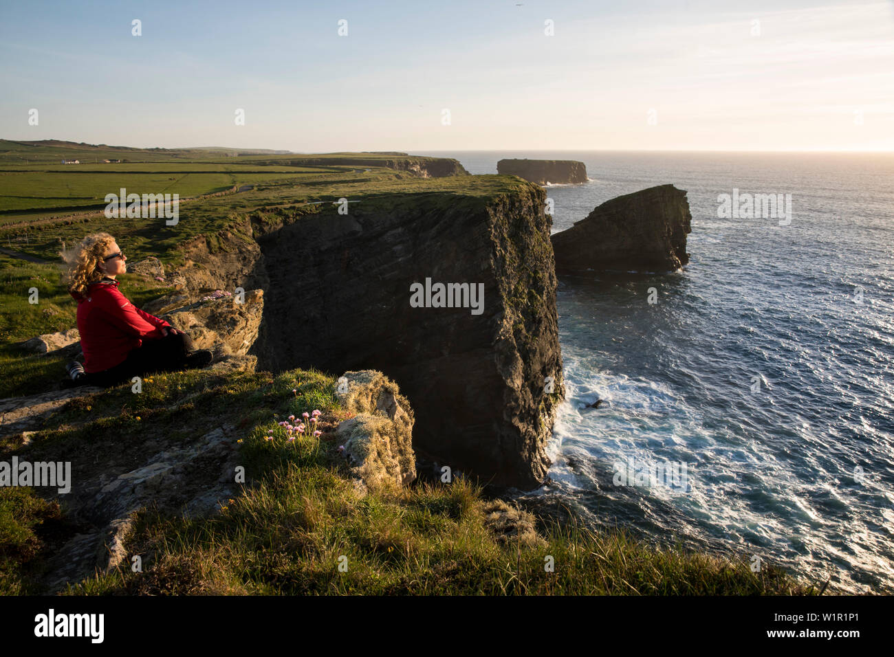 Woman sits on cliffs edge hi-res stock photography and images - Alamy