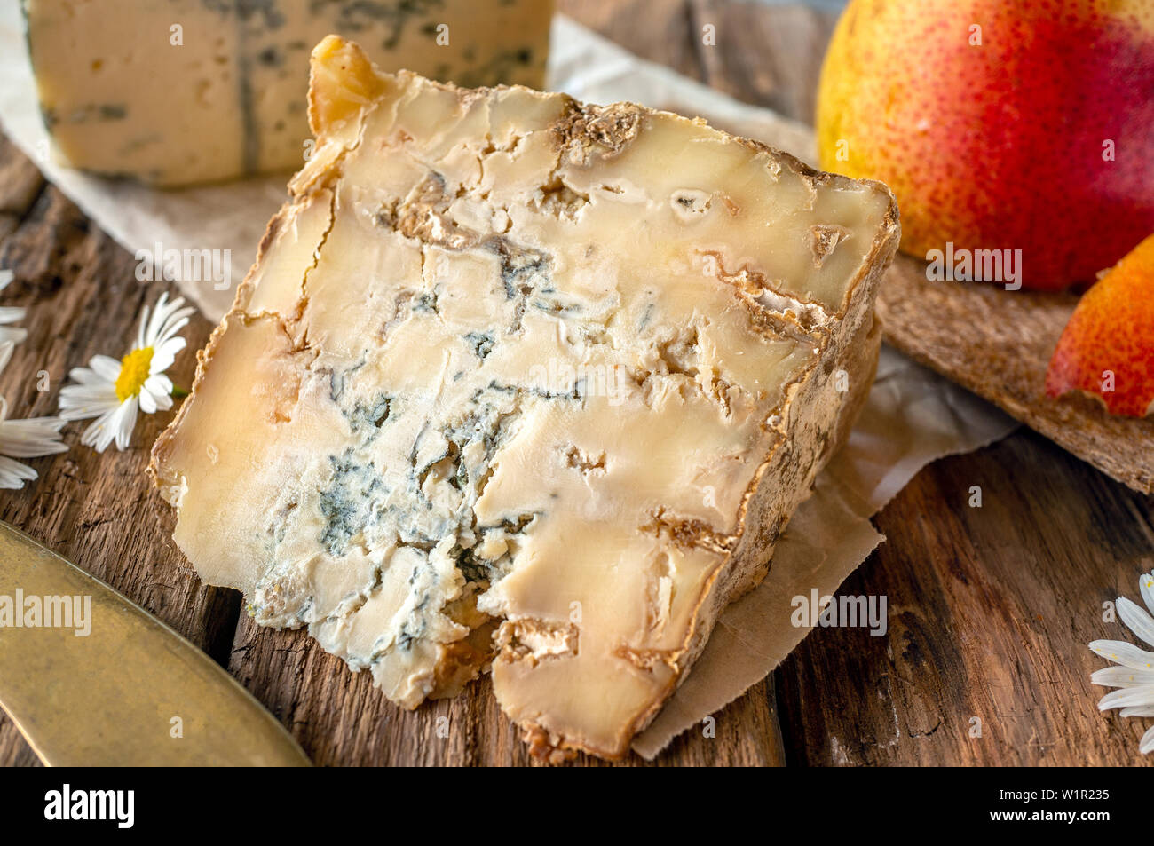 A slice of blue aged Stilton cheese on a wooden table. Cheese is served ...