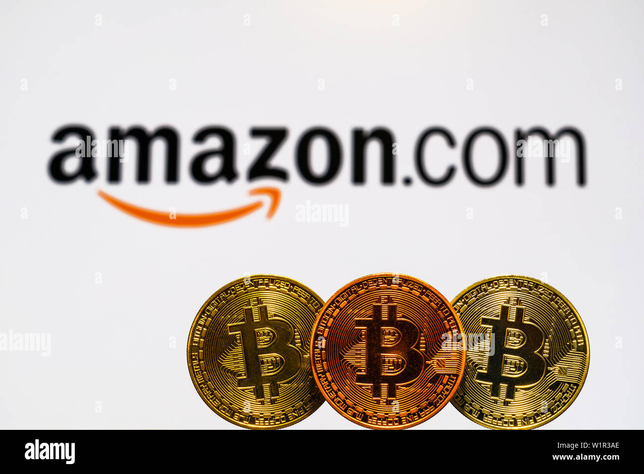 Gold Bitcoin coins with the Amazon logo on background screen. A new ...