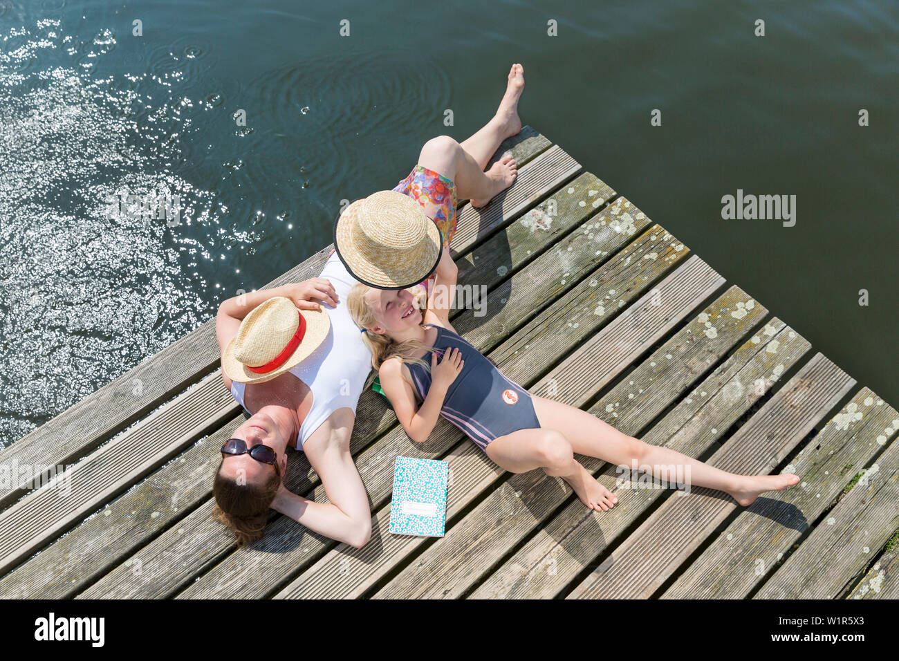 Mother And Daughter Lying On Swimming Platform Reading Sunbathing Straw Hat Swimming In A