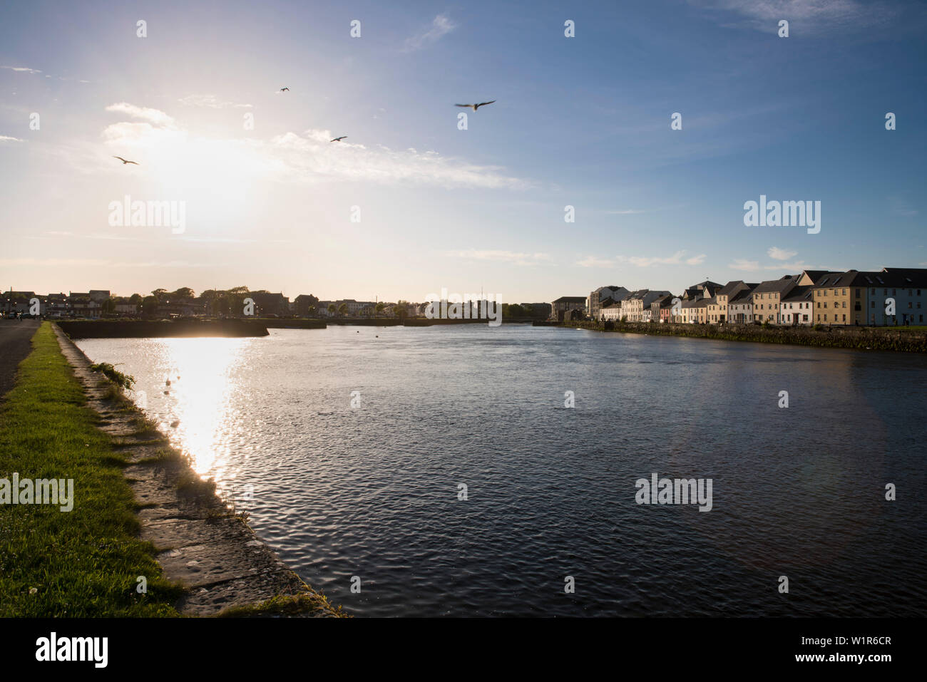 Birds fly as the sun sets over the Corrib river at Galway harbour ...