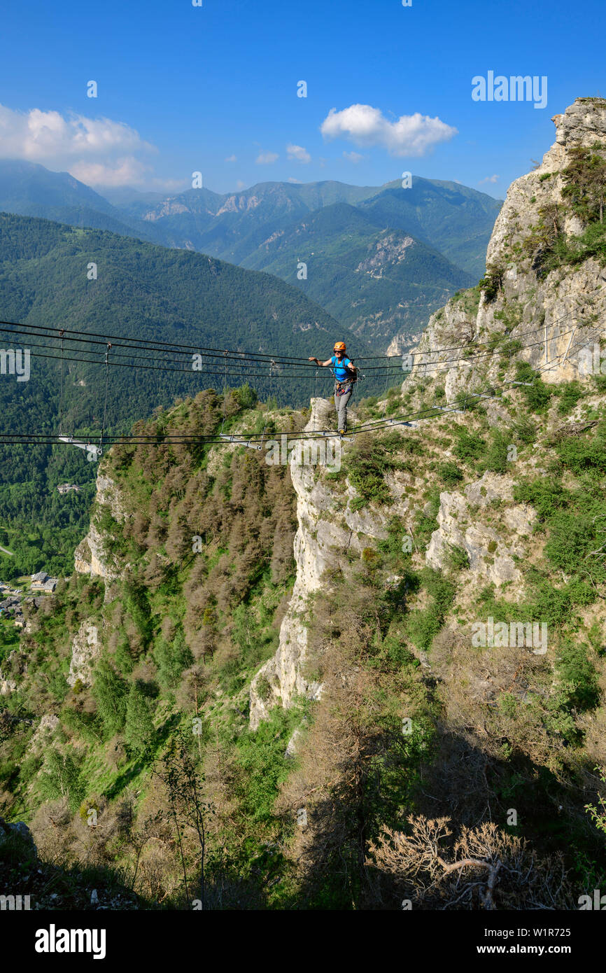 Woman climbing fixed rope route crossing ropeway, Ferrata di ...