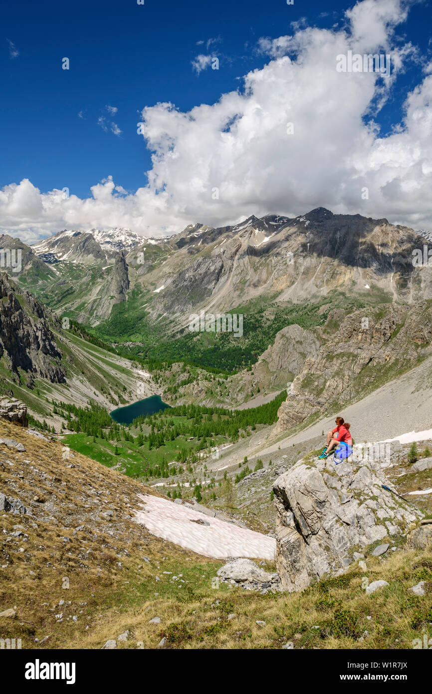 Woman hiking sitting on rock and looking towards valley, mountain lake ...